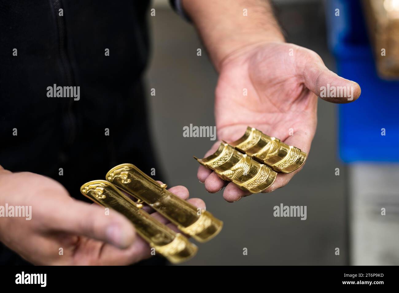 Two hands holding polished casings for the scabbards of edged weapons ...