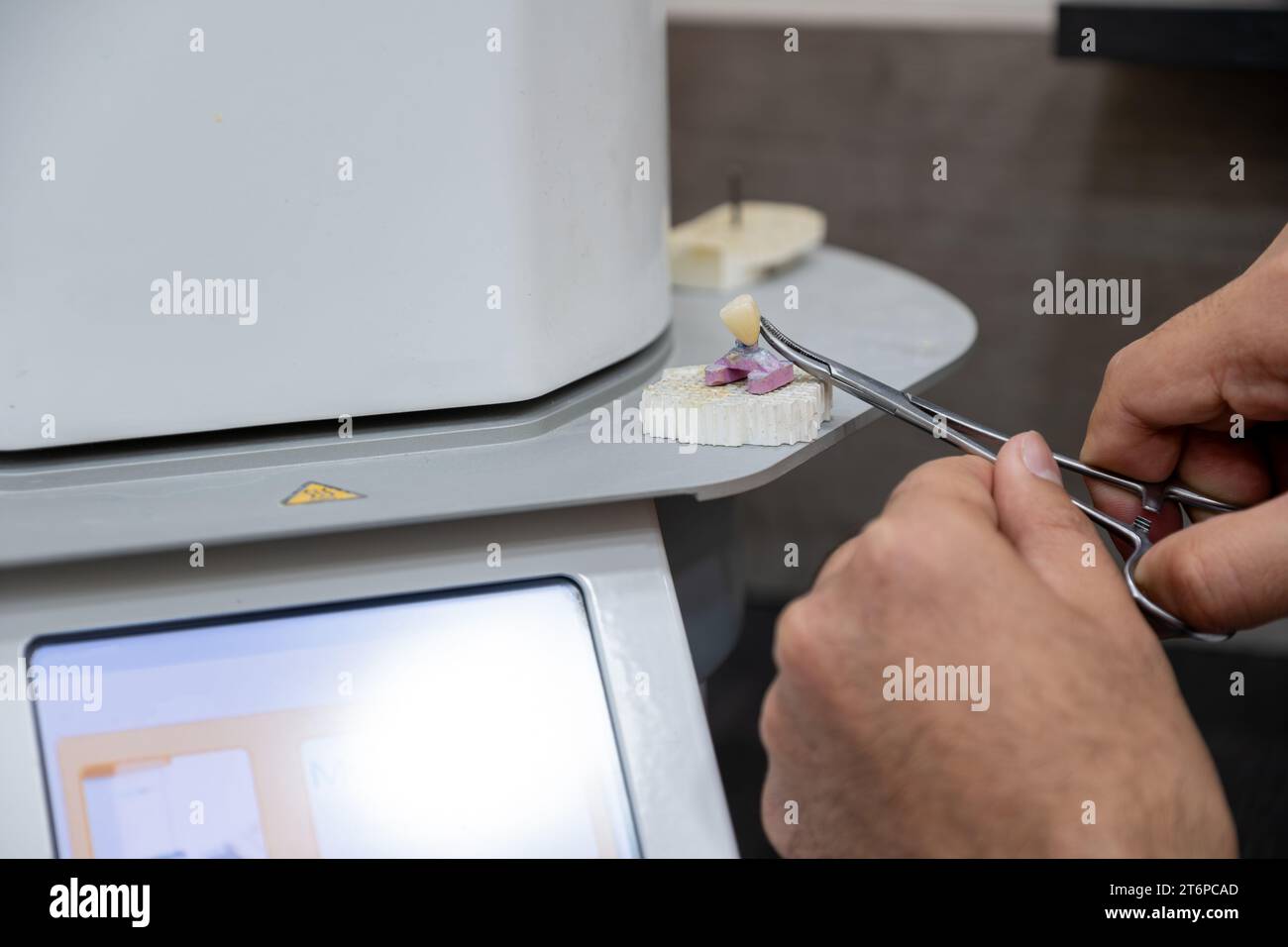 Technician operates high temperature furnace to bake prosthetic ceramic ...