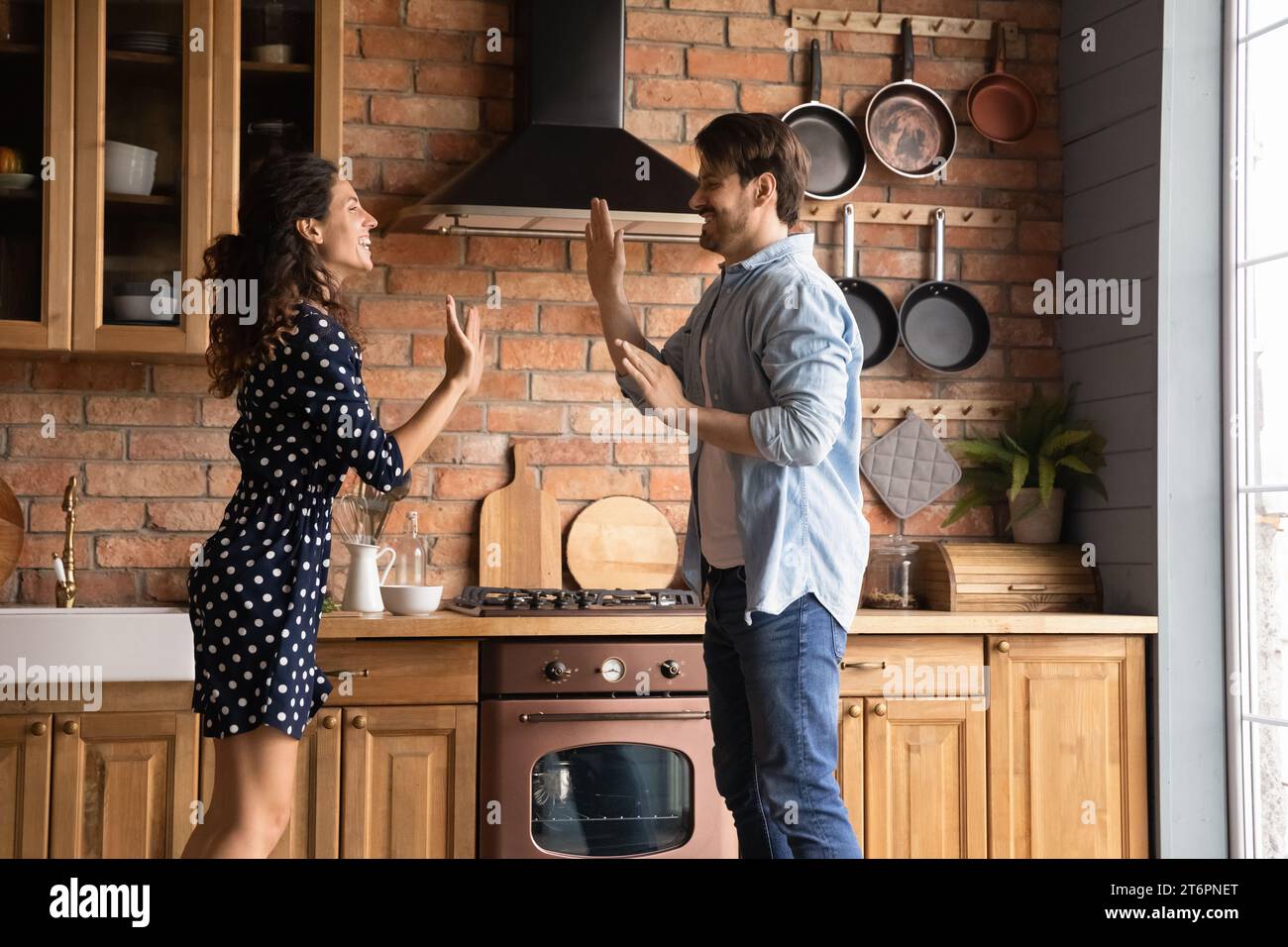 Overjoyed millennial couple clapping hands, having fun in cozy kitchen ...