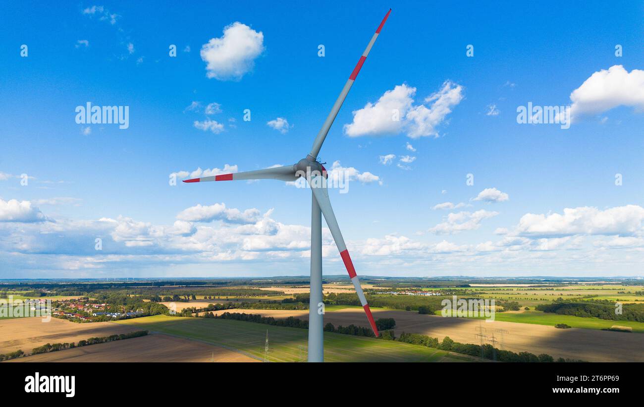 An aerial view of a modern white and red wind turbine on a rural field ...