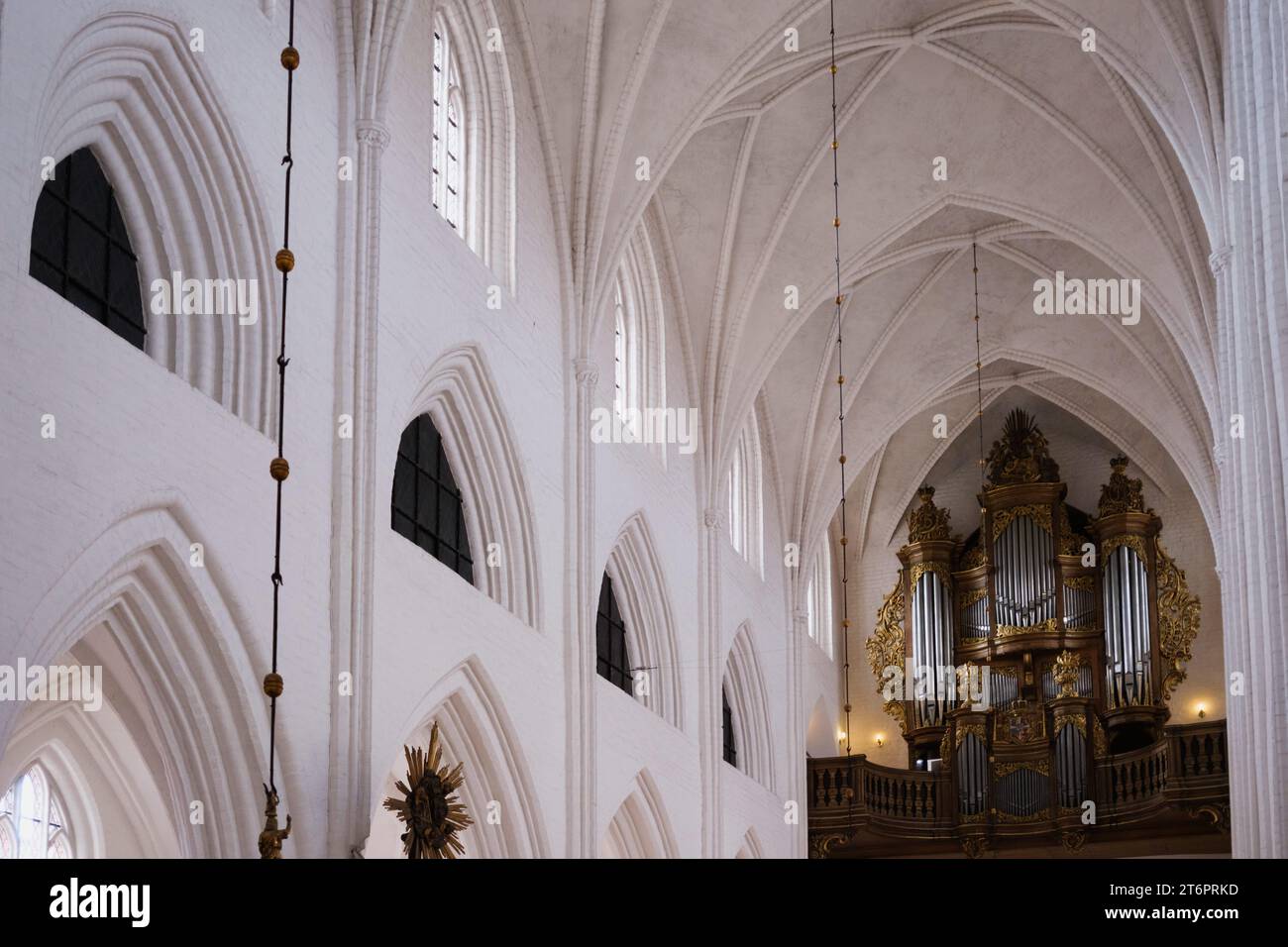 Interior of a simple cathedral, white corridors and dark wooden pews ...