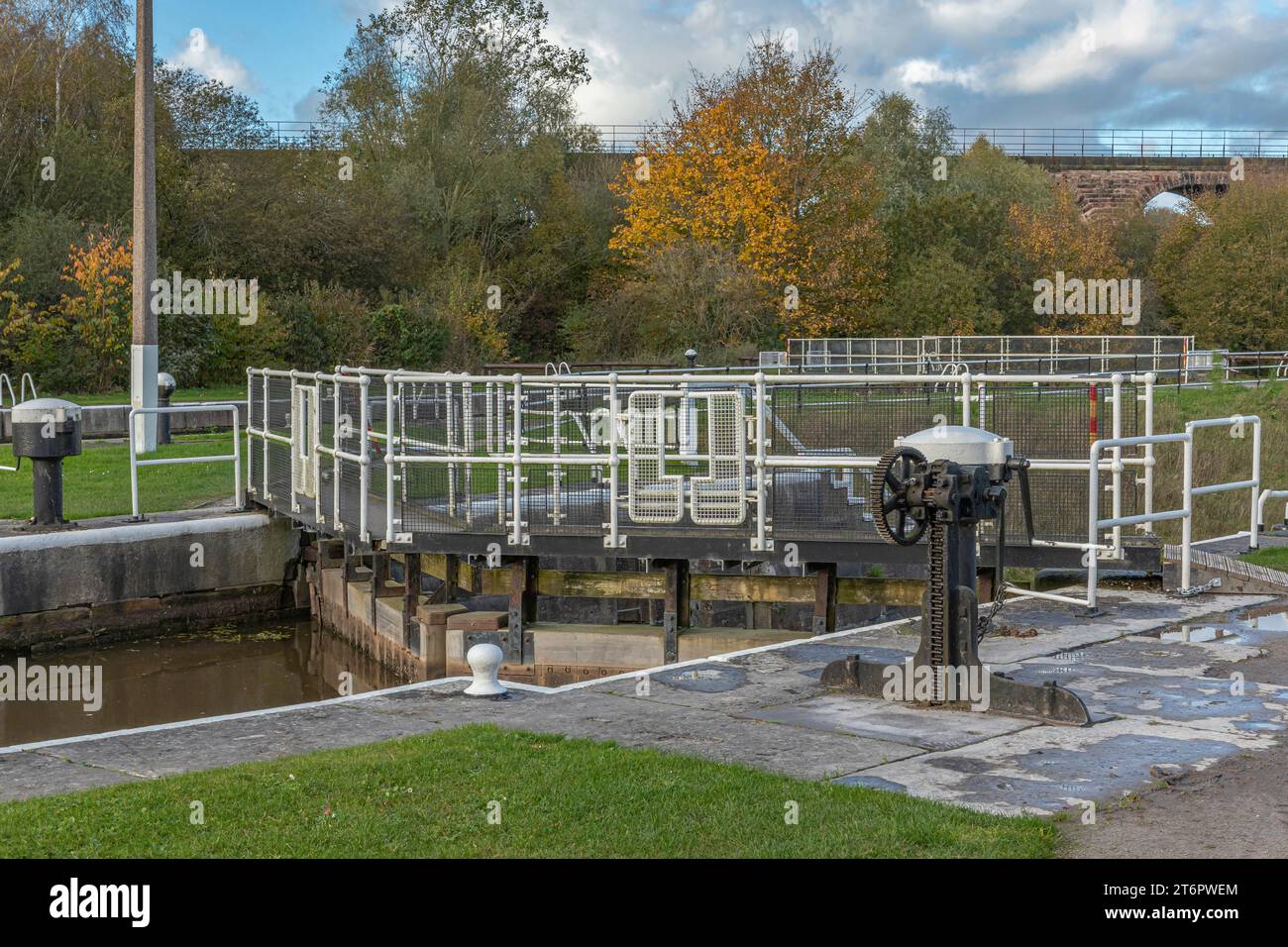 Lock gates closed with water behind them and a small bridge across the ...