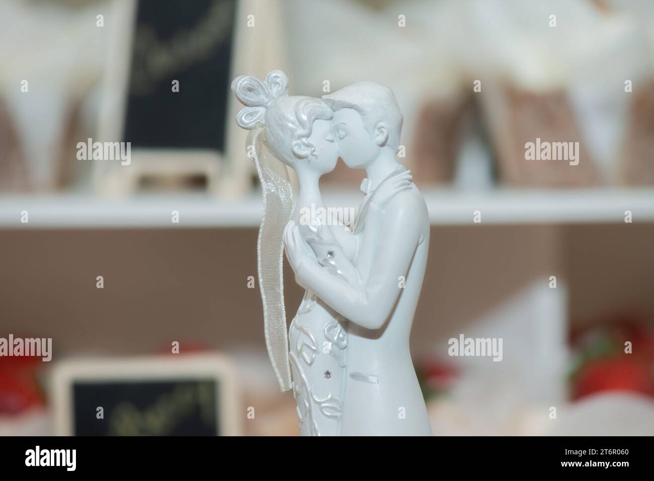 Bride and groom passionately kissing ceramic cake toppers on top of ...