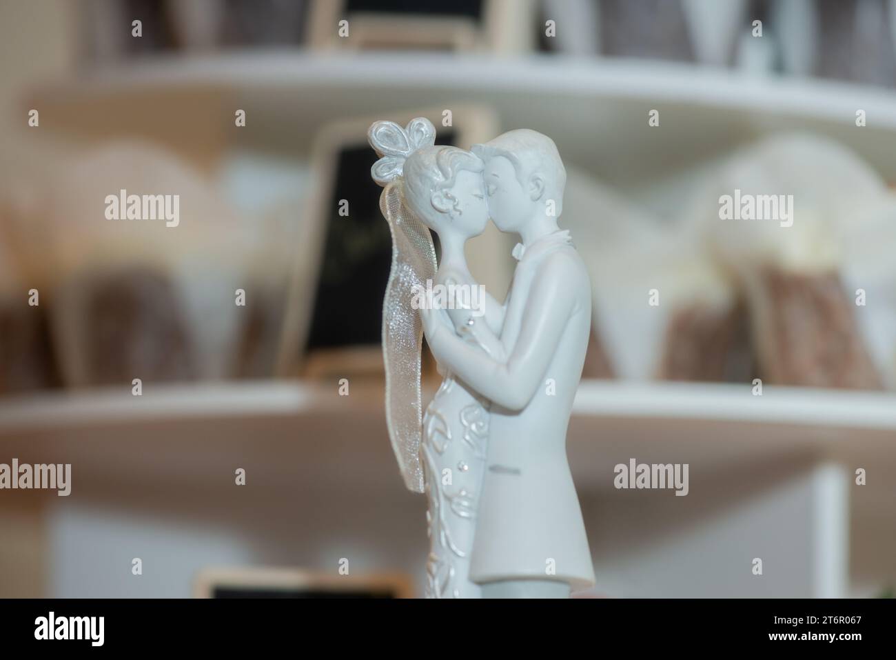 Bride and groom passionately kissing ceramic cake toppers on top of ...
