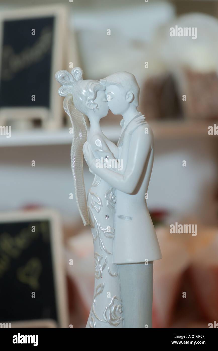 Bride and groom passionately kissing ceramic cake toppers on top of ...