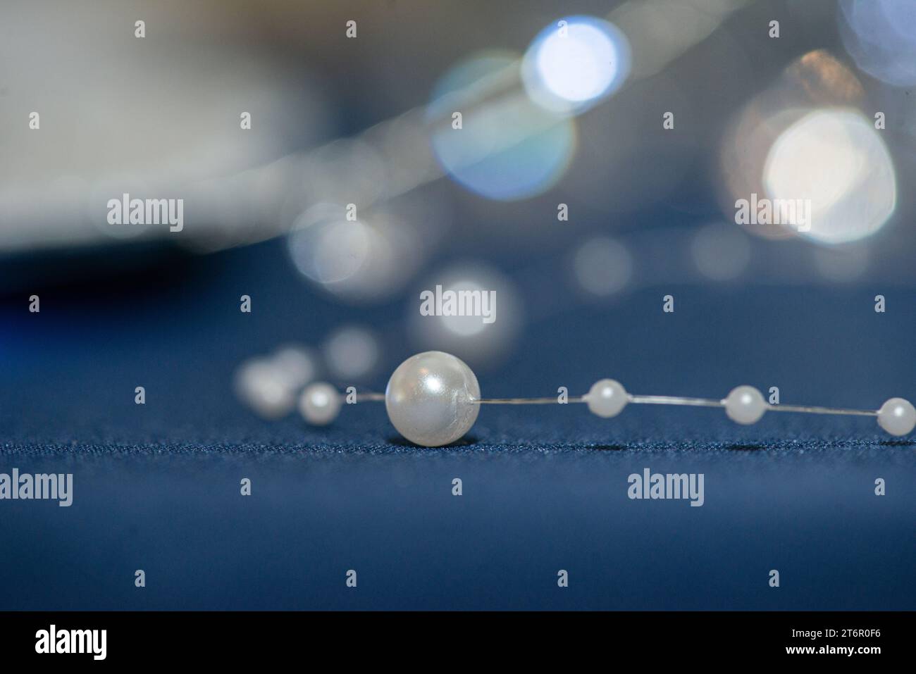 String of white pearls different sizes on blue surface with blue and ...