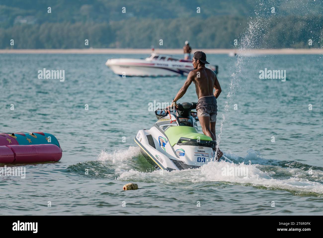 Very well fit man safely drive jet ski from shore to open sea. Tropical ...