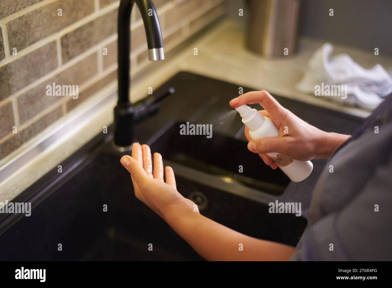 Close-up woman holding white mockup bottle of antiseptic and spraying ...