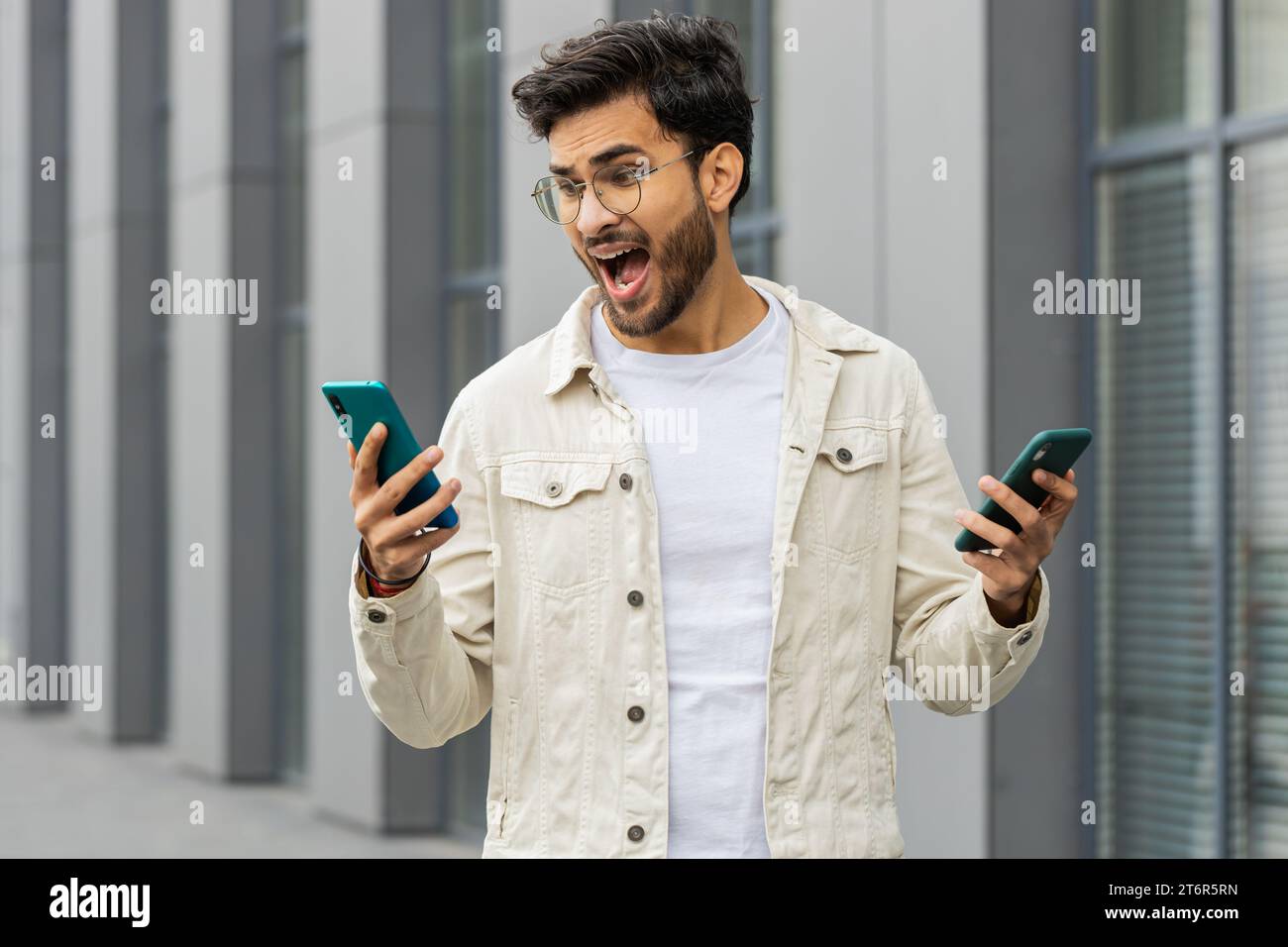 Irritated nervous stressed Indian man talking screaming on two mobile ...