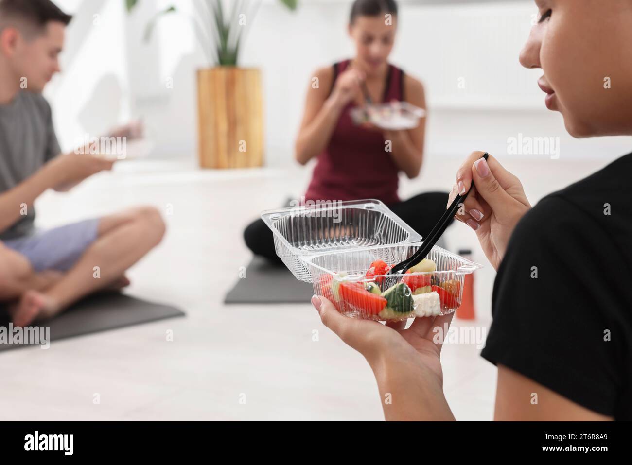 Group of people eating healthy food after yoga class indoors, closeup ...