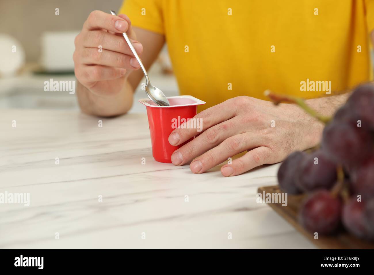 Man with delicious yogurt at white marble in kitchen, closeup Stock ...