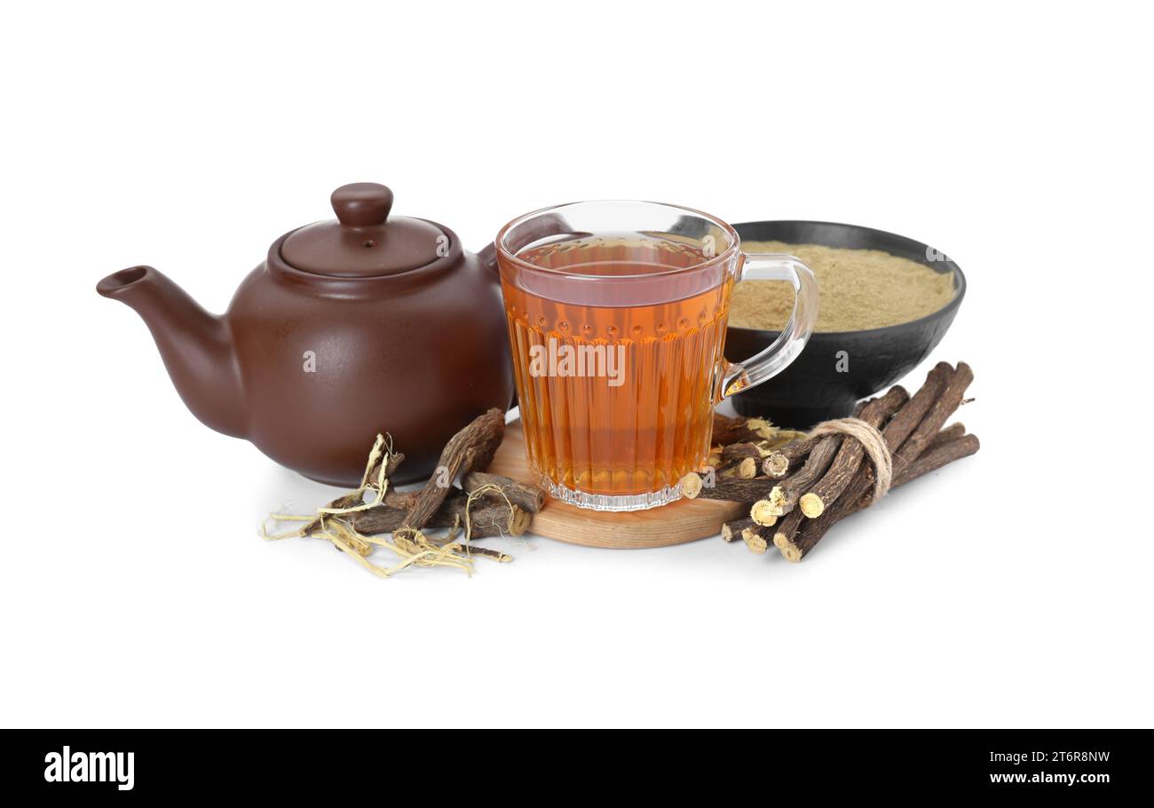 Aromatic licorice tea in cup, teapot, dried sticks of licorice root and ...