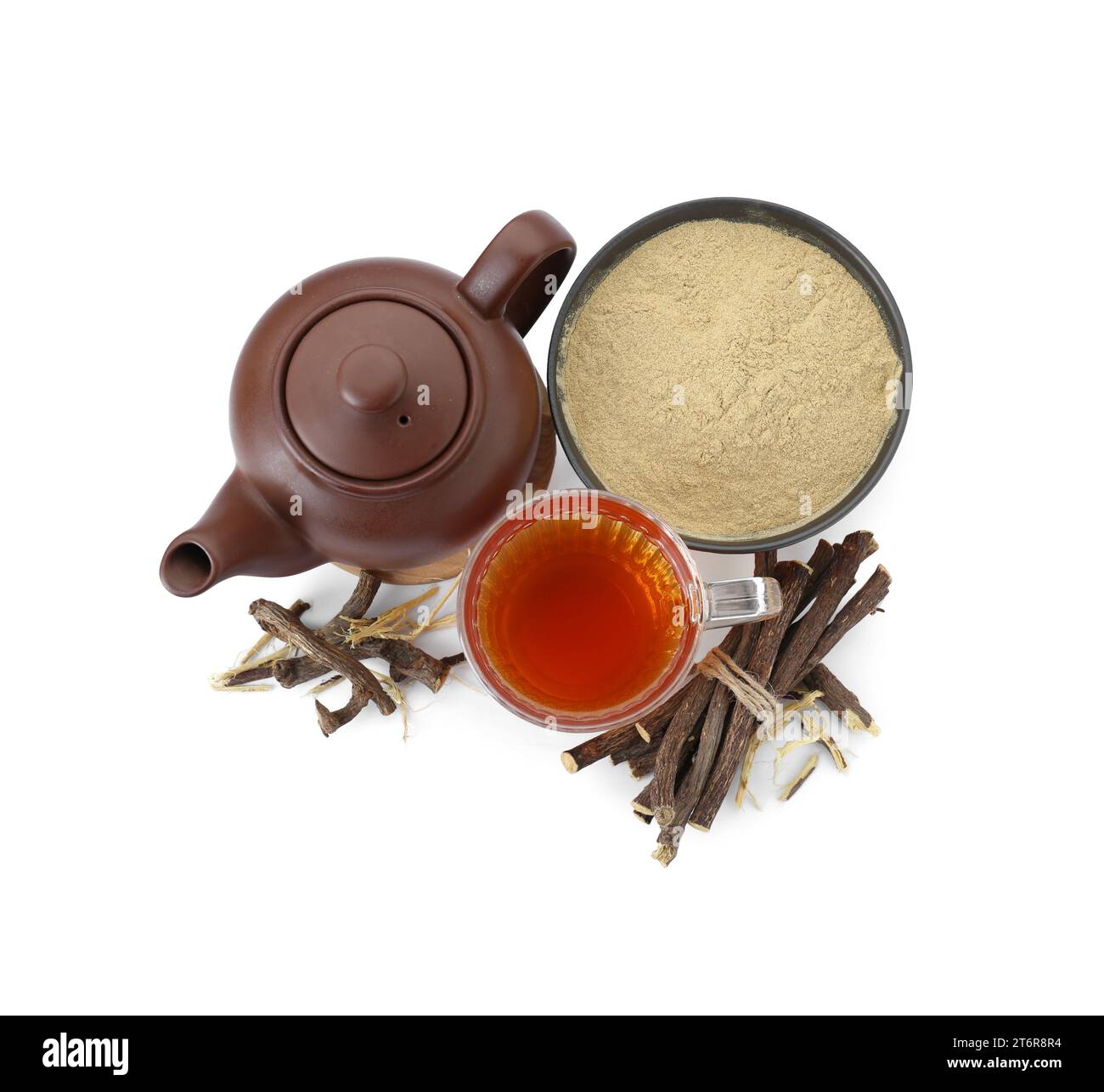 Aromatic licorice tea in cup, teapot, dried sticks of licorice root and ...