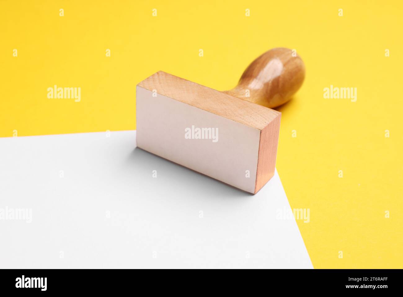 One wooden stamp tool and sheet of paper on yellow background, closeup ...