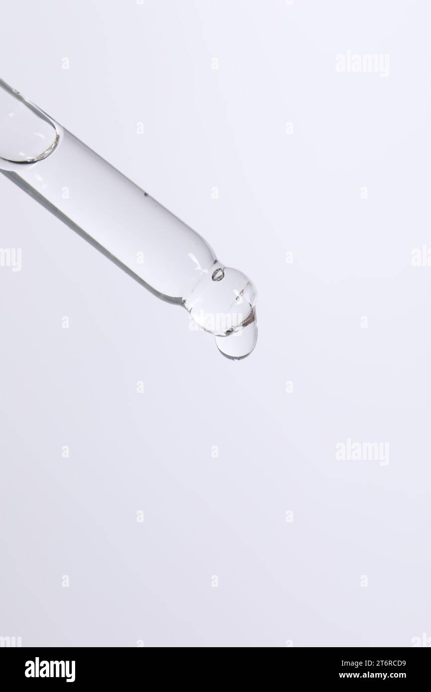 Dripping cosmetic serum from pipette on white background Stock Photo ...