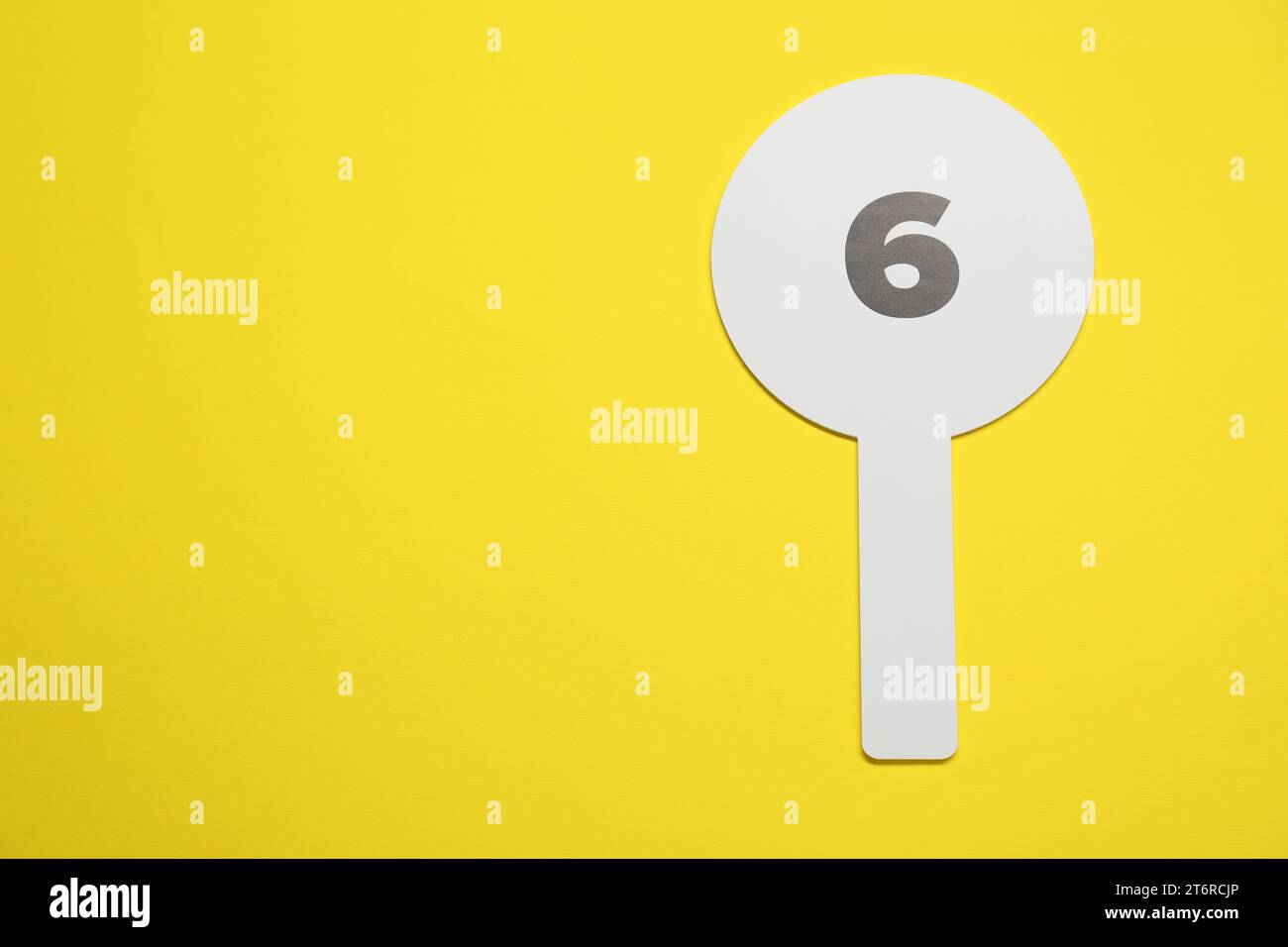 Auction paddle with number 6 on yellow background, top view. Space for ...