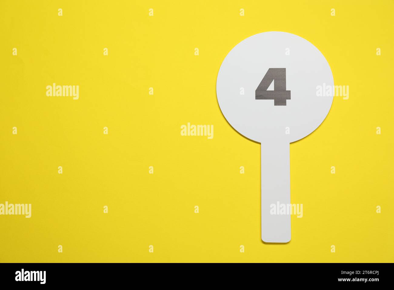 Auction paddle with number 4 on yellow background, top view. Space for ...