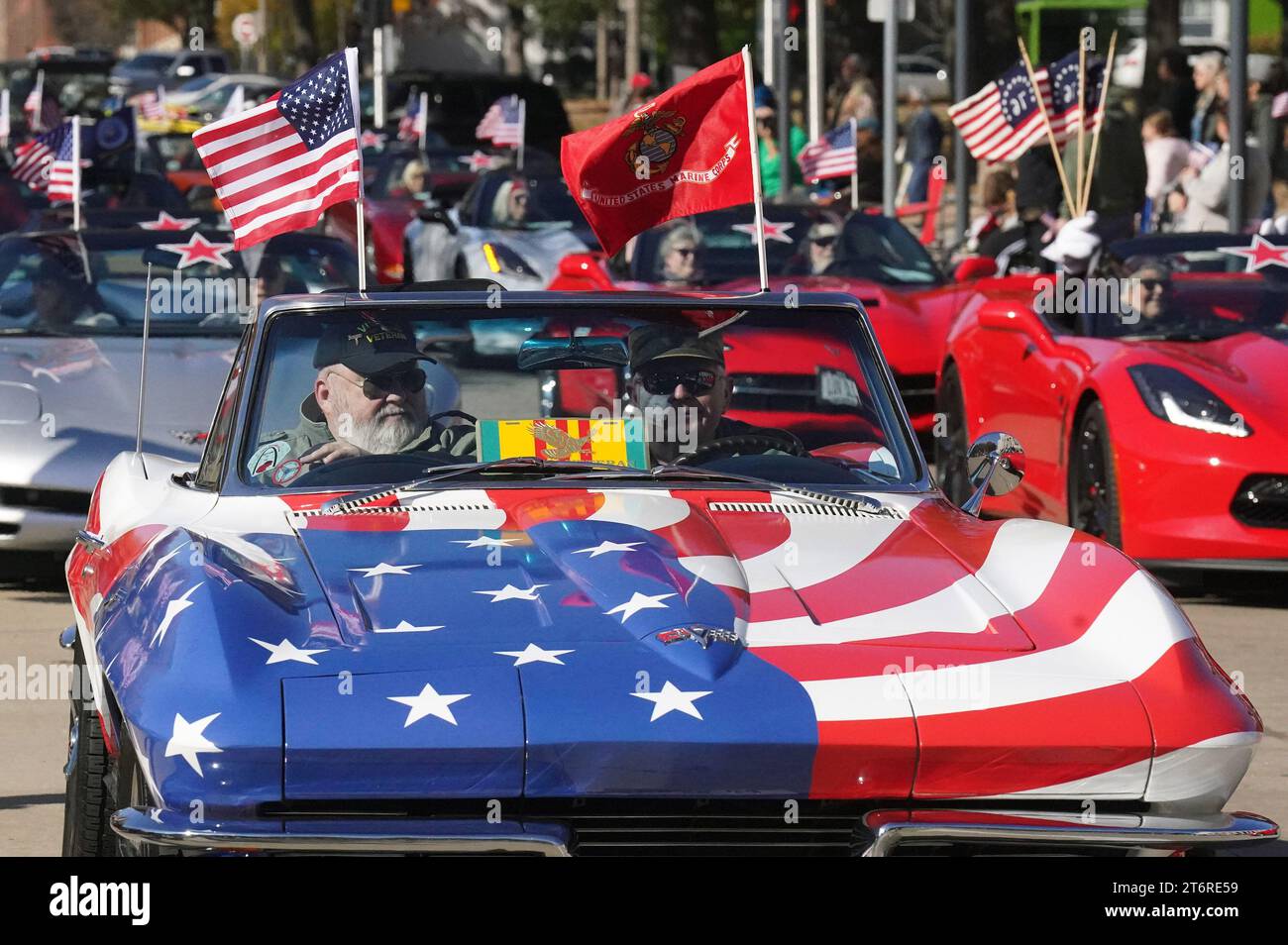 Veterans wave to bystanders from a Corvette painted as an American flag ...