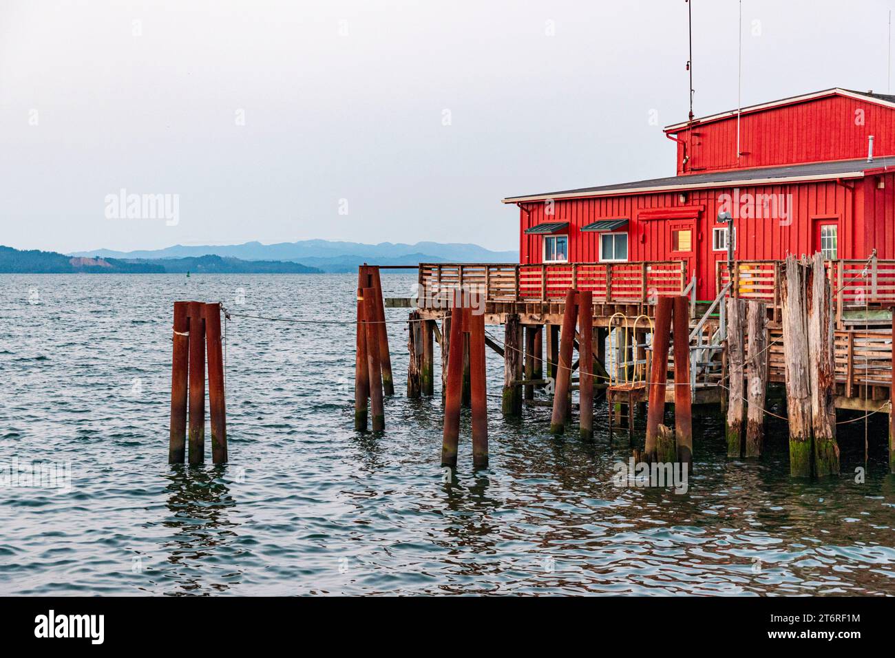 A bright red wooden building sits atop a pier that juts out into the ...