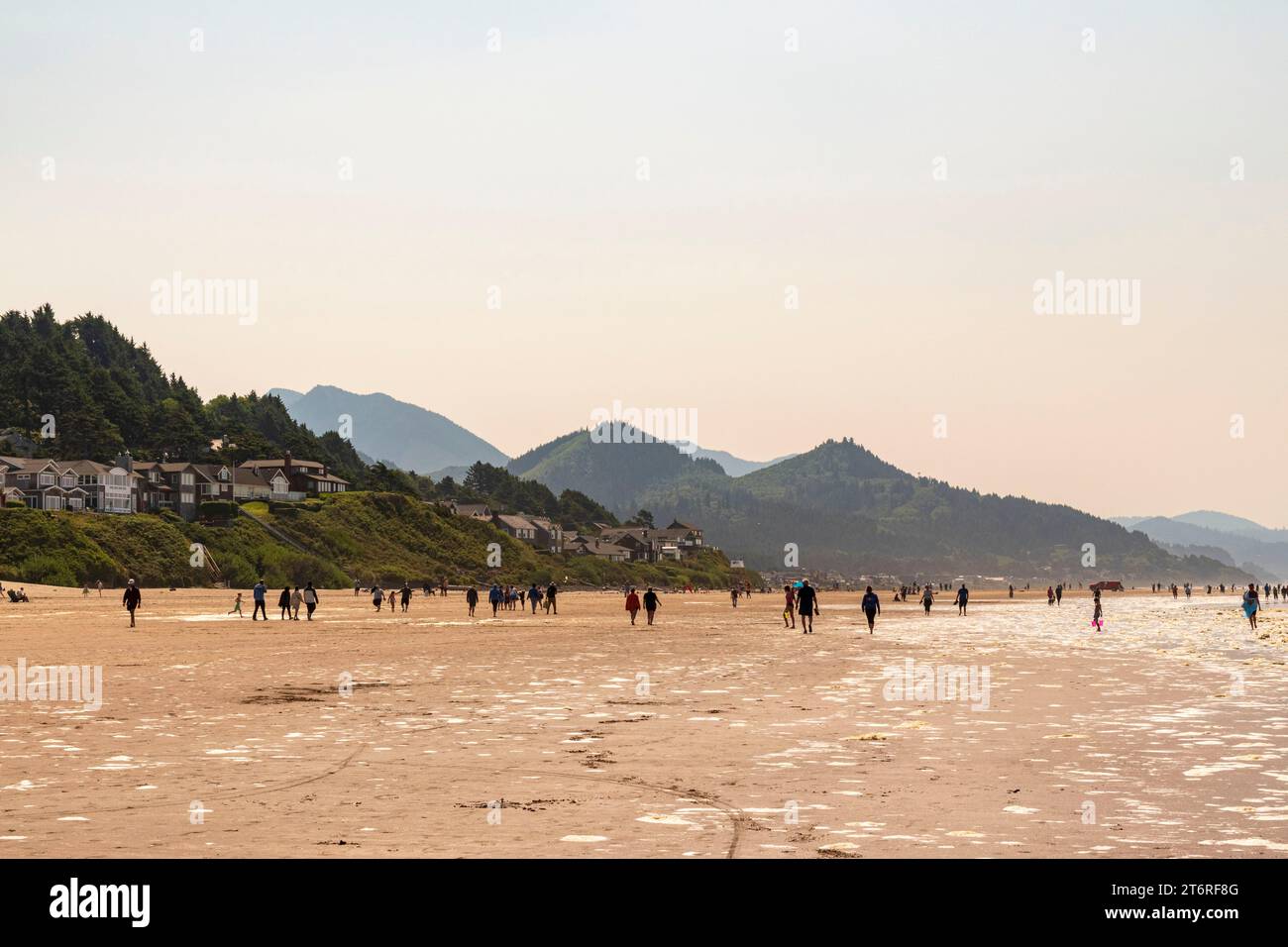 Green hills of evergreen trees rise above crowded Cannon Beach, Oregon ...