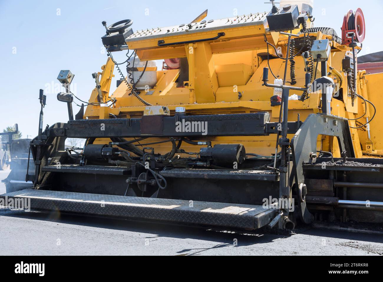 During highway construction, pavement machine lays fresh bitumen ...