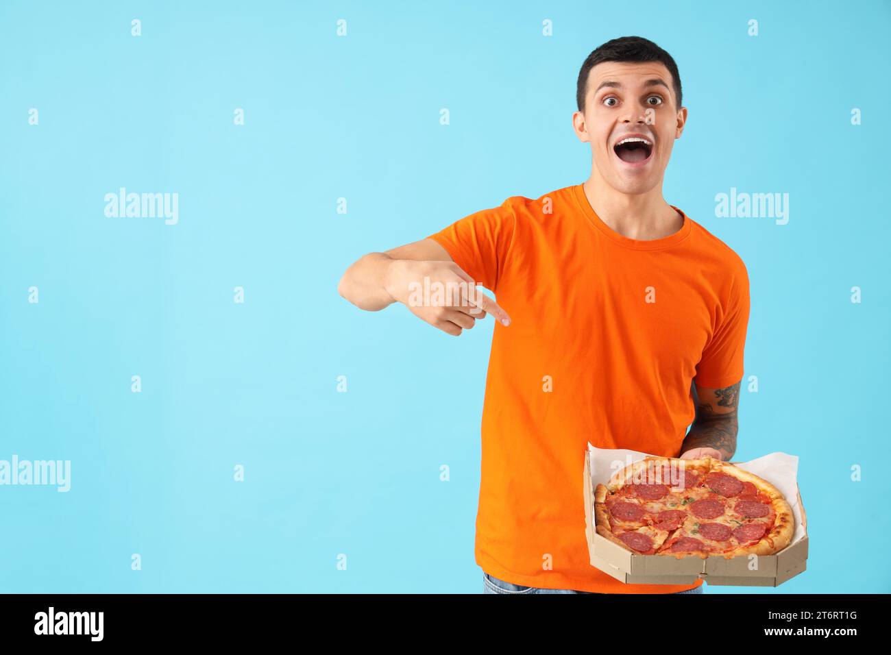 Young man pointing at tasty pepperoni pizza on blue background Stock ...