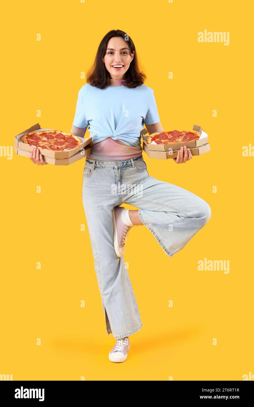 Young woman with tasty pepperoni pizza on yellow background Stock Photo ...