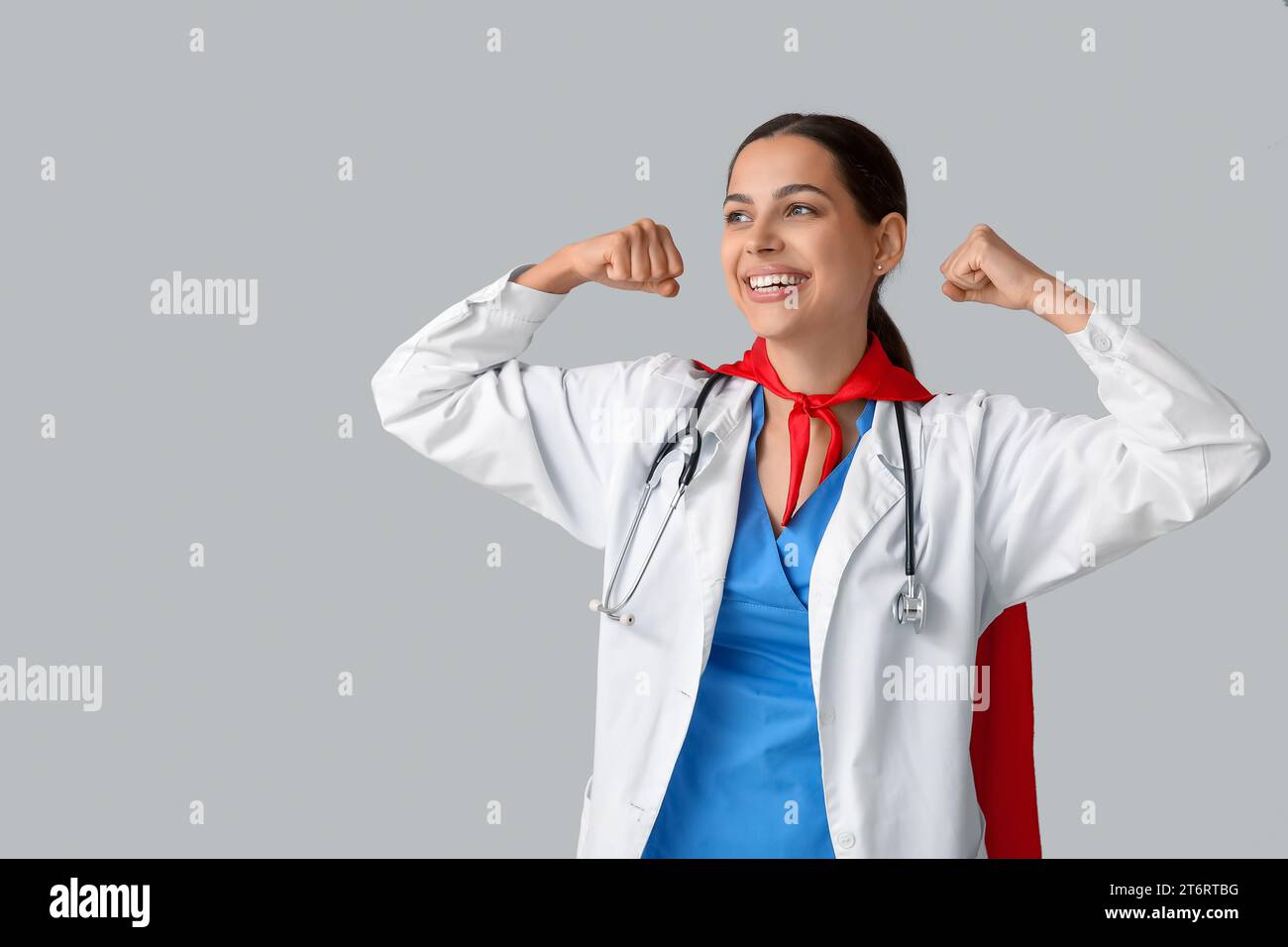 Beautiful female doctor in superhero costume showing muscles on white ...