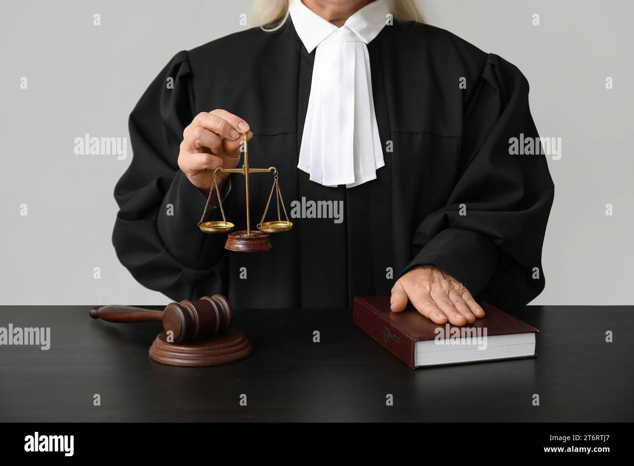 Female judge with scales of justice and book at table on grey ...