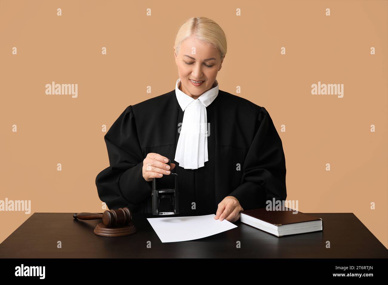 Mature female judge with stamp and document at table on brown ...