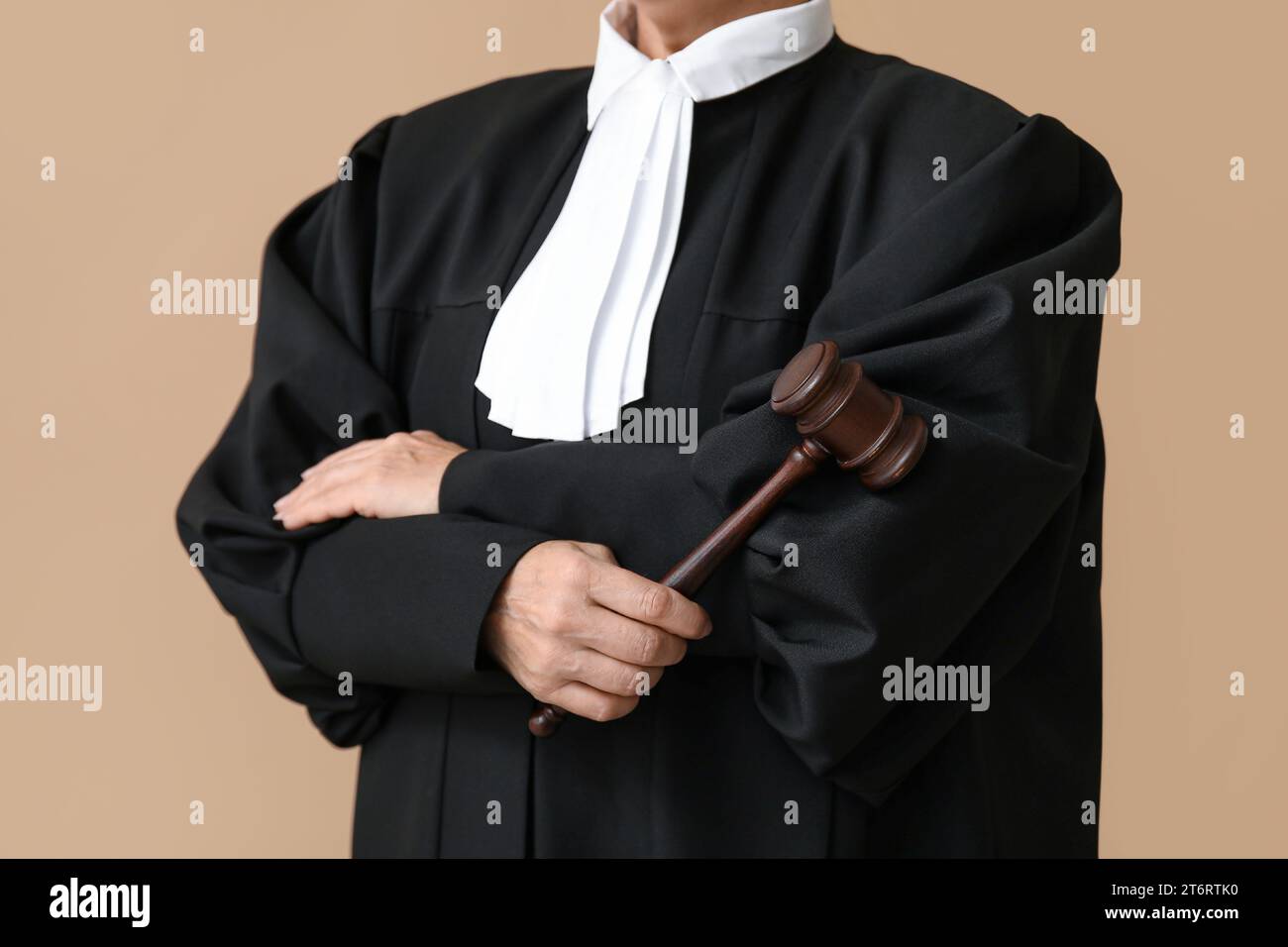 Female judge with crossed arms and gavel on brown background Stock ...