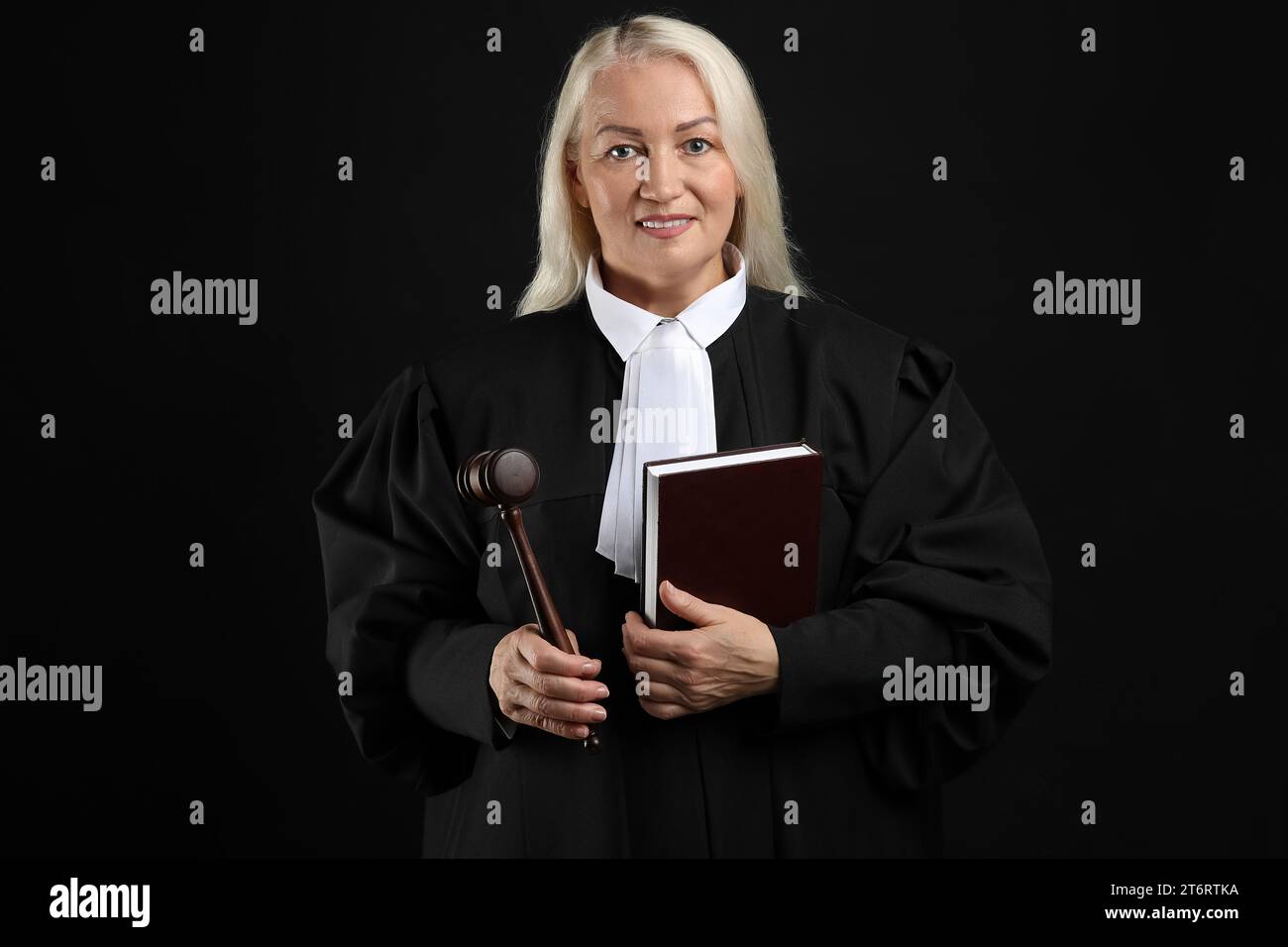 Mature female judge with book and gavel on black background Stock Photo ...