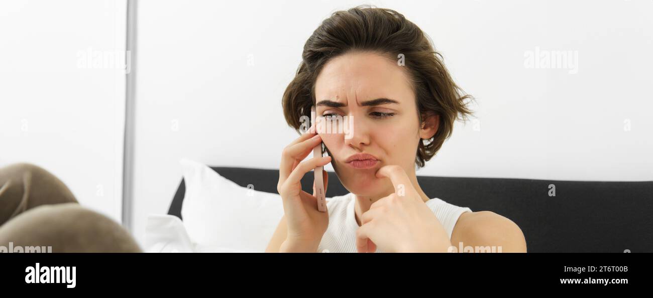 Close up portrait, woman makes a phone call with puzzled, frowning face ...
