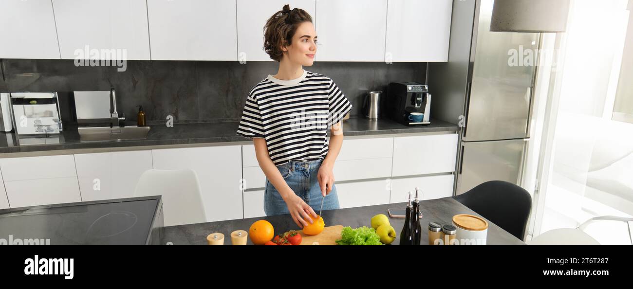 Portrait of young female model cooking in the kitchen, chopping ...