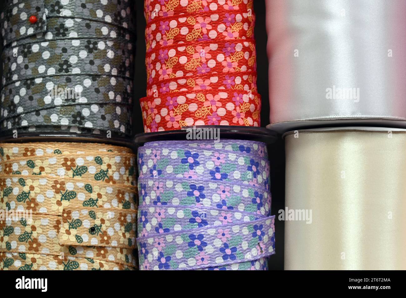Colourful rolls of patterned and plain textile ribbons in haberdashery ...