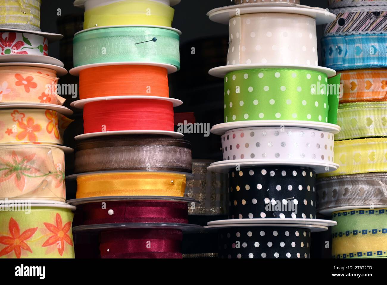 Colourful rolls of patterned and plain textile ribbons in haberdashery ...