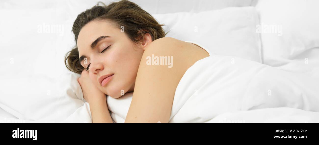 Woman lying asleep in her bed, eyes closed, face is calm and relaxed ...