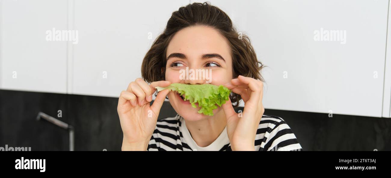 Cute smiling woman eating lettuce leaf and smiling, having a healthy ...