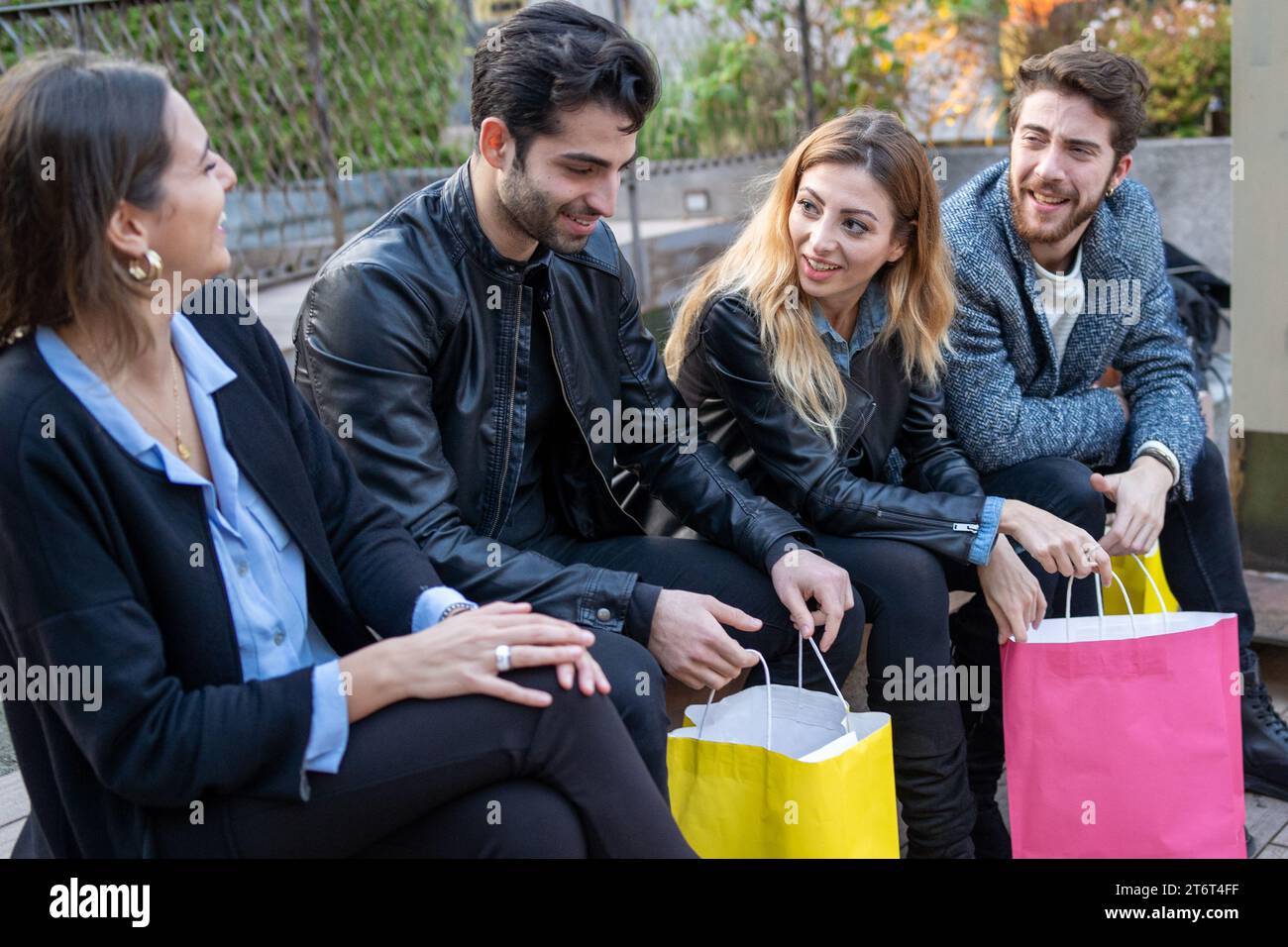 Four young adults sitting together - happy friends sharing a joyful ...