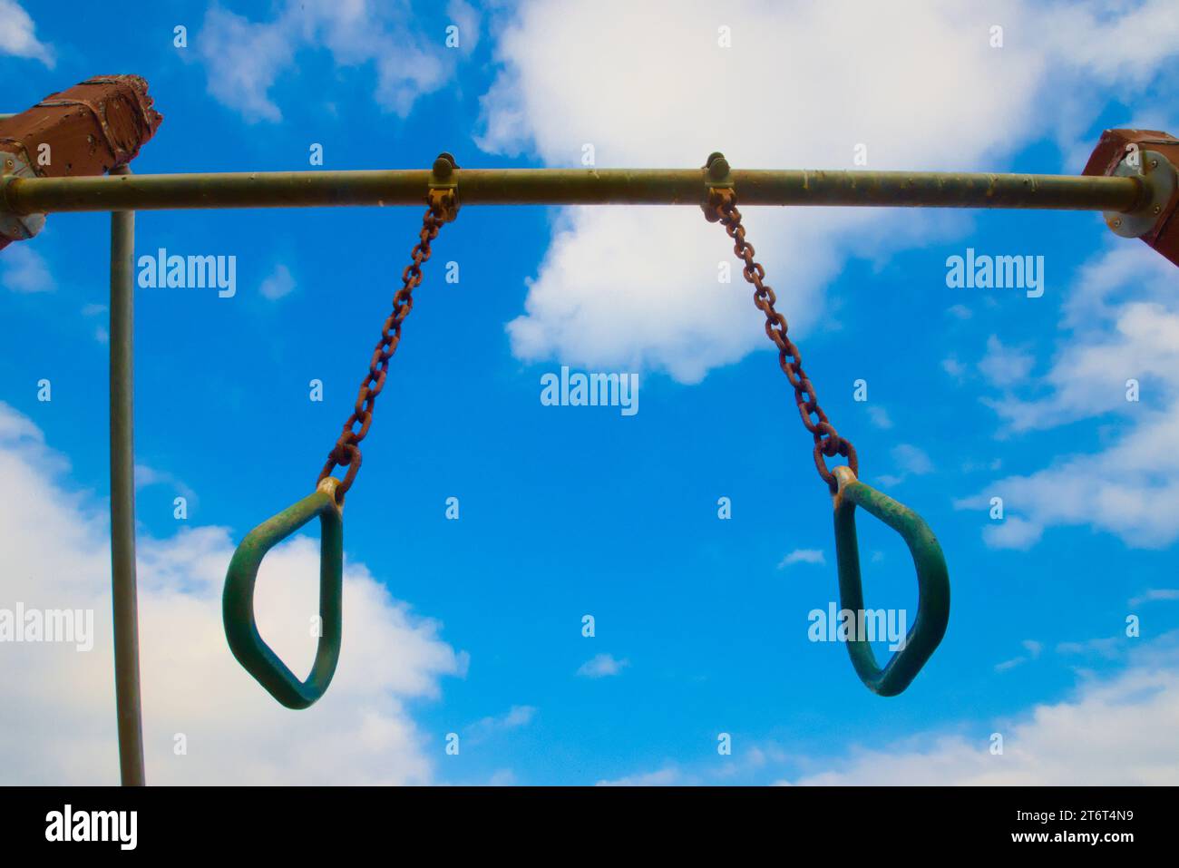 Pair of exercise rings hangs on an outdoor training bar. A dramatic ...