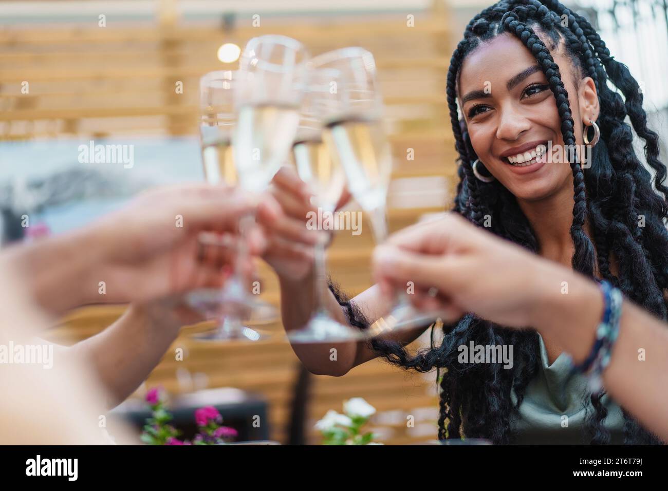 A radiant woman with braided hair toasting with champagne glasses among ...