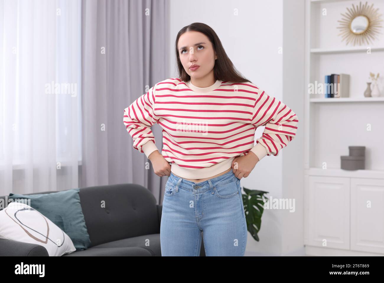 Confused woman trying to put on tight jeans at home Stock Photo - Alamy