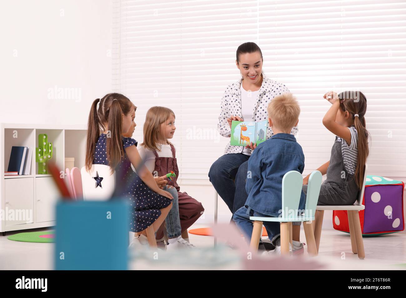 Nursery teacher and group of cute little children learning animals in ...