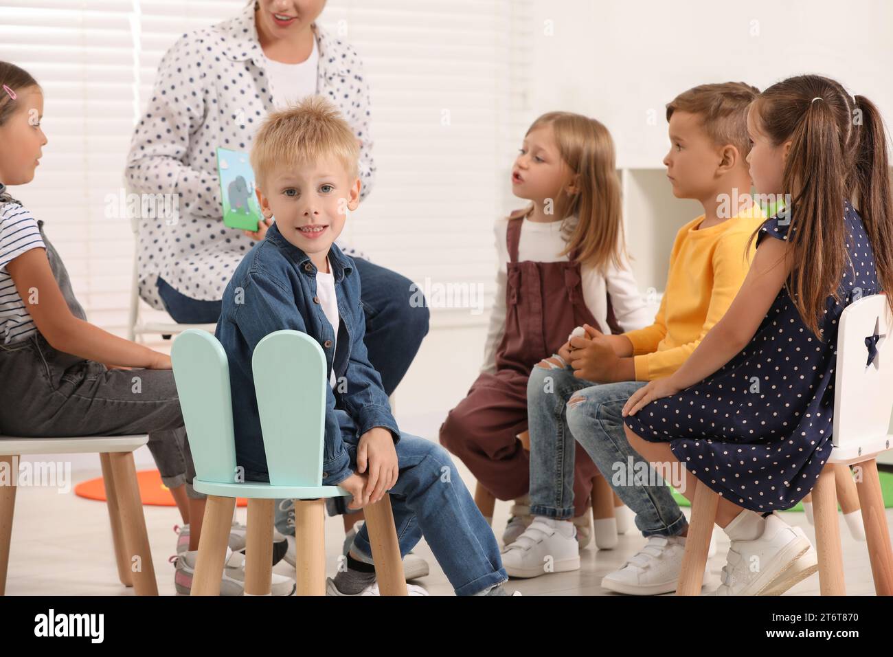 Nursery teacher and group of cute little children studying in ...