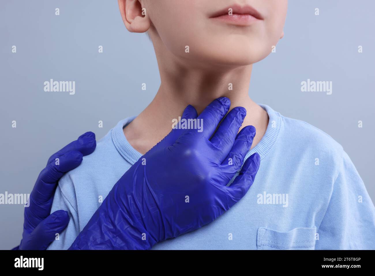 Endocrinologist examining boy's thyroid gland on light grey background ...