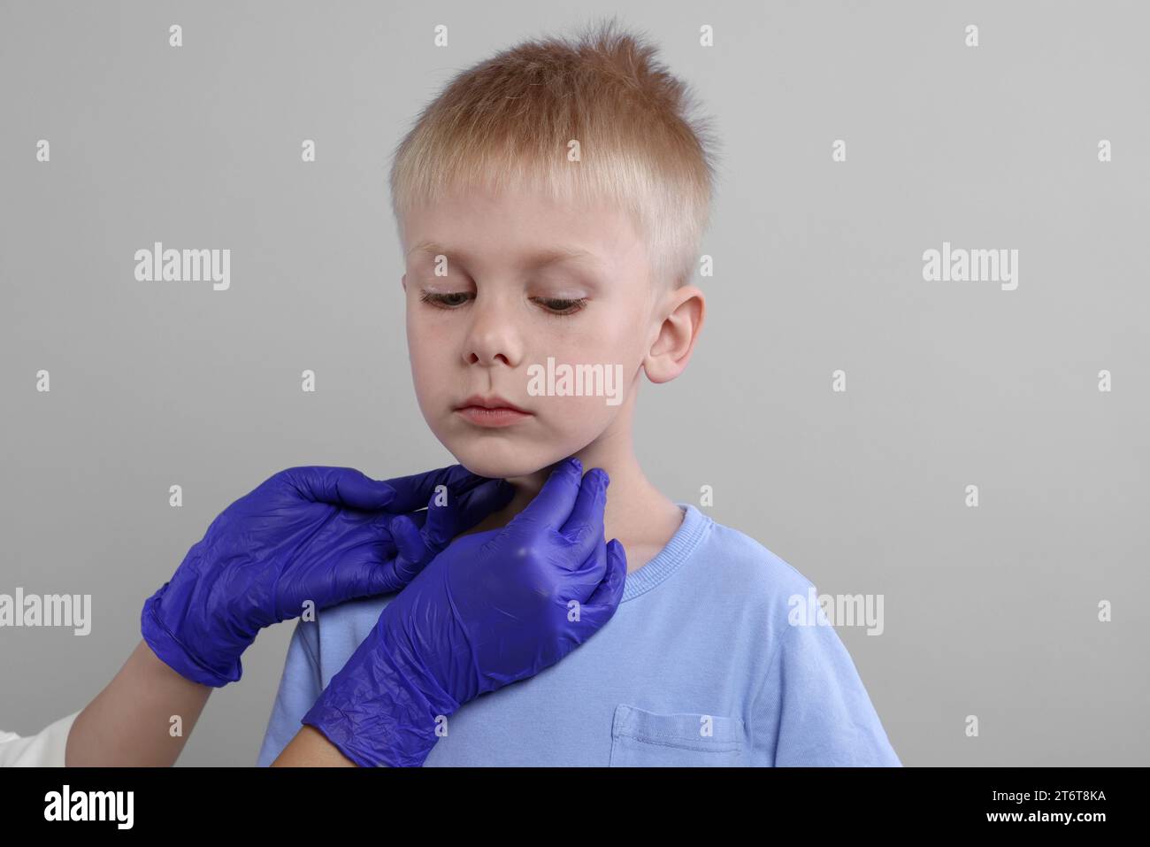 Endocrinologist examining boy's thyroid gland on light grey background ...