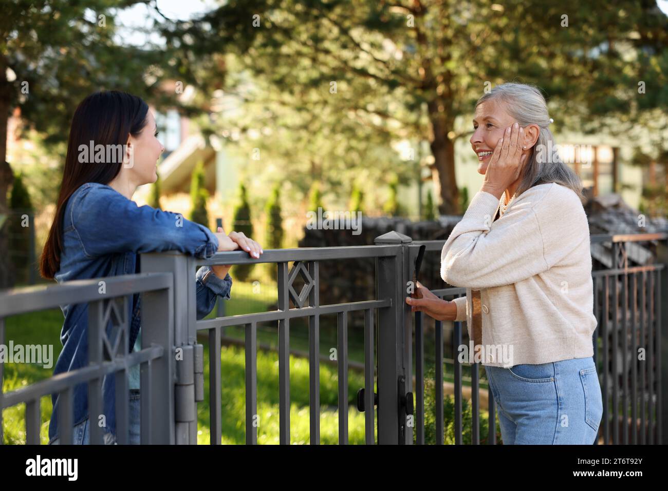 Friendly relationship with neighbours. Happy women talking near fence ...