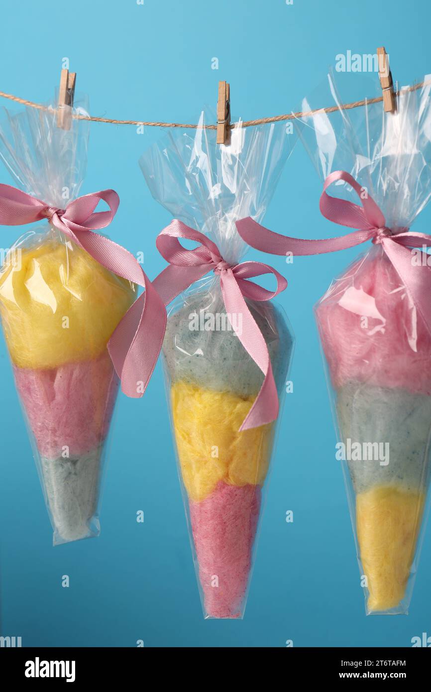 Packaged sweet cotton candies hanging on clothesline against light blue ...