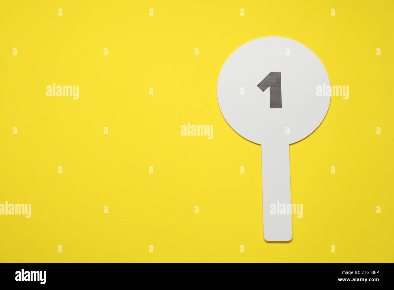 Auction paddle with number 1 on yellow background, top view. Space for ...
