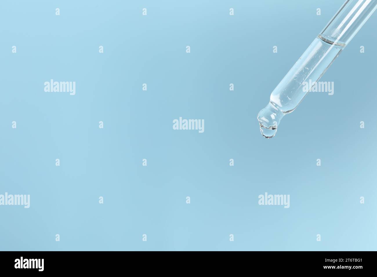 Dripping cosmetic serum from pipette on light blue background, space ...